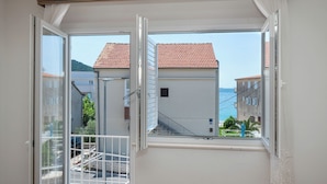 Uma varanda com vista para uma cidade costeira, um corrimão branco e céu claro.