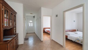 Corredor que dá para um quarto com cama, um armário de madeira e uma porta.