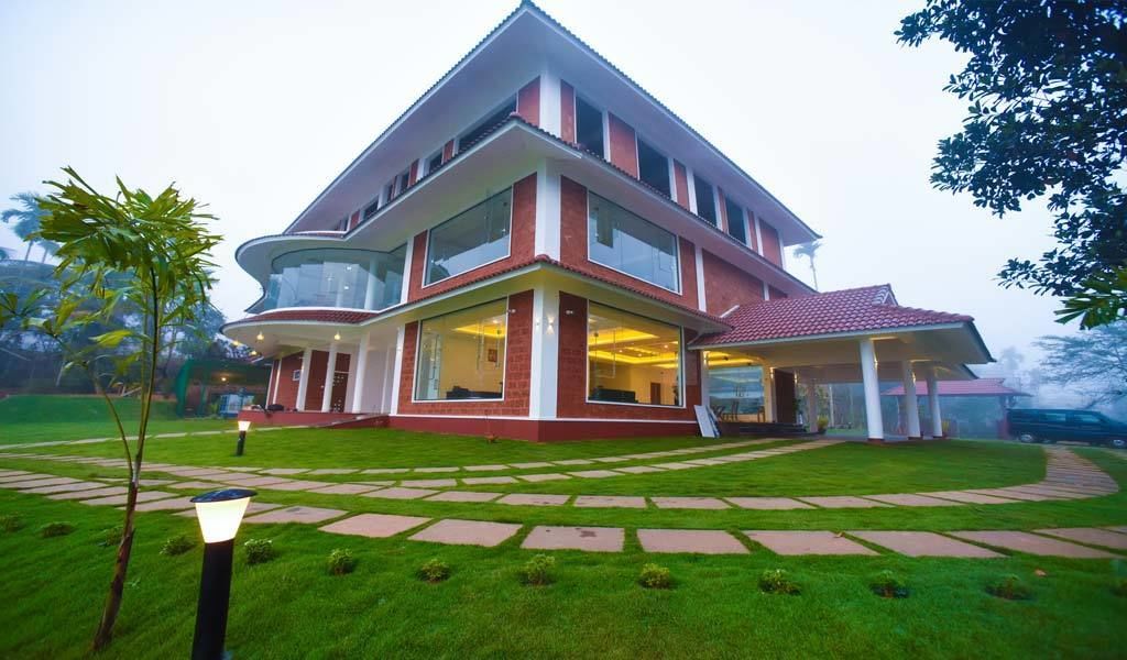 Uma casa moderna de dois andares com fachada curva, janelas amplas e um gramado bem cuidado.