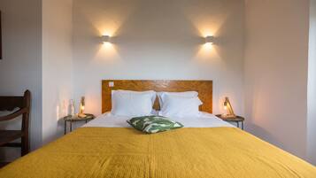 Uma cama bem arrumada com cabeceira de madeira, duas luminárias de apoio e um travesseiro com padrão verde.