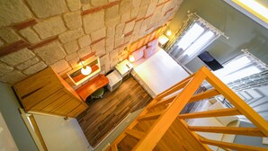 Quarto com parede de pedra, móveis de madeira e uma cama.