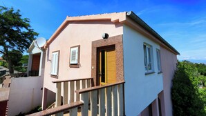 Uma casa de dois andares com varanda, antena parabólica e porta com janela.