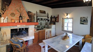 Uma cozinha rústica com lareira de tijolos, armários de madeira e uma mesa de jantar.