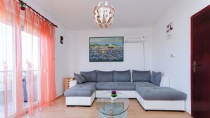 Uma sala de estar moderna com um sofá modular, uma mesa de centro de vidro e um quadro na parede.