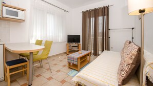 Quarto de hotel pequeno, com cama, mesa, televisão e micro-ondas.