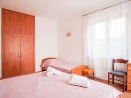Quarto com duas camas, guarda-roupa de madeira e uma janela com cortinas.