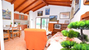 Uma sala de estar acolhedora com uma mesa de jantar, uma poltrona laranja e uma televisão.