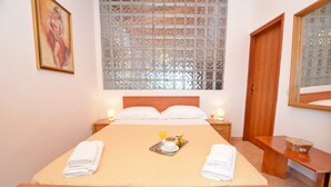 Cama bem arrumada com toalhas, um tabuleiro com itens de café da manhã e uma janela com um painel decorativo.