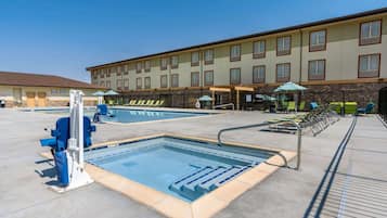 Uma área de piscina de hotel com várias piscinas, espreguiçadeiras e guarda-sóis.