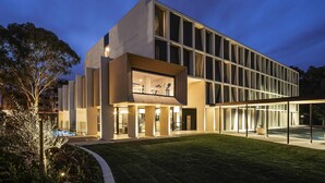 Um edifício moderno com telhado plano, janelas amplas e um gramado bem cuidado.