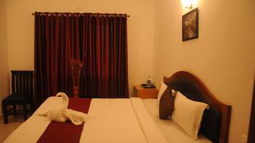 Quarto de hotel com cama, mesa de cabeceira, uma cadeira e luminária fixada na parede.