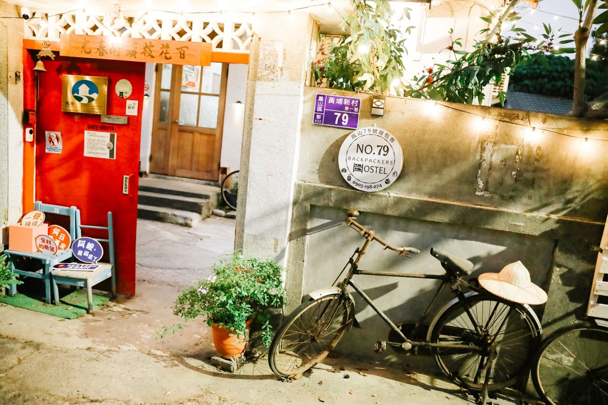 Uma bicicleta estacionada ao lado de um muro com uma placa indicando uma hospedaria.