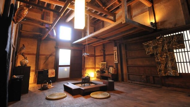 Um quarto japonês tradicional com tatames, vigas de madeira e um lanterna pendurada.