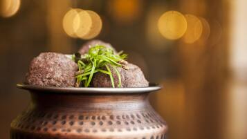 Uma panela de cobre tradicional com um prato de comida, possivelmente um prato do Oriente Médio, com um fundo desfocado de luzes bokeh quentes.