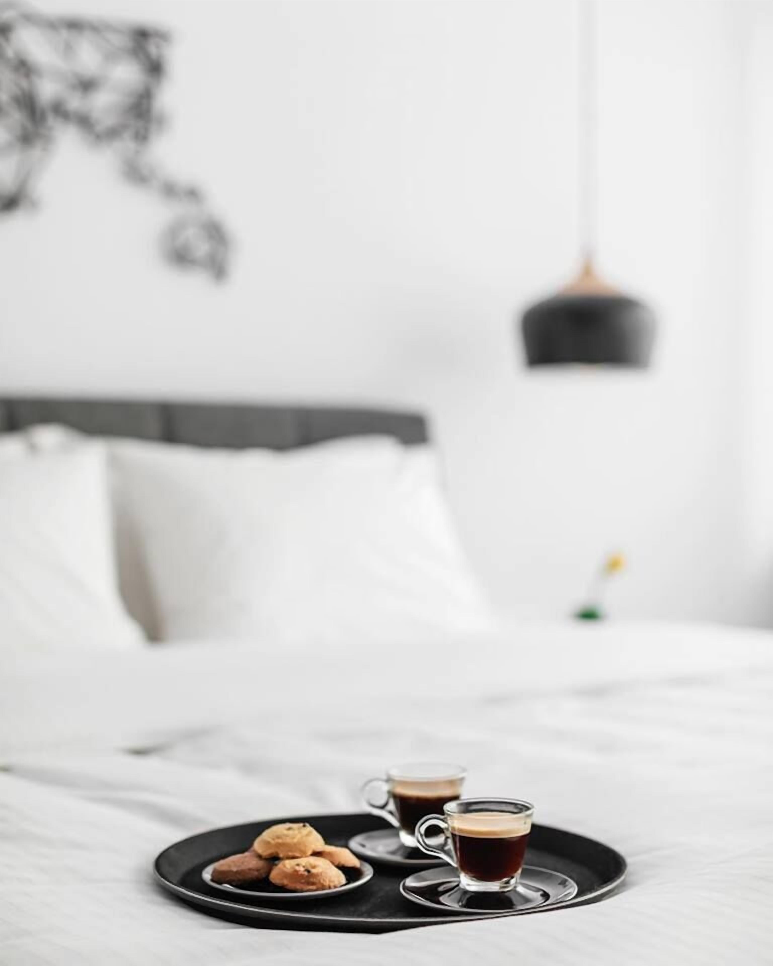 Uma bandeja com biscoitos e duas xícaras de café sobre a cama.