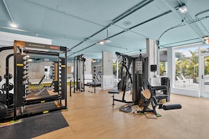 Uma academia com diversos equipamentos de exercício, incluindo um suporte para agachamento e bancos de peso.