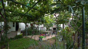 Um jardim com área de recreação, um edifício branco e uma escadaria que leva à entrada.