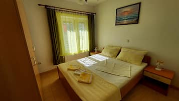 Quarto bem arrumado com cama, mesa de cabeceira, cortinas e um quadro na parede.
