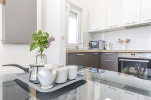 Uma cozinha moderna com armários brancos, micro-ondas, forno e janela.
