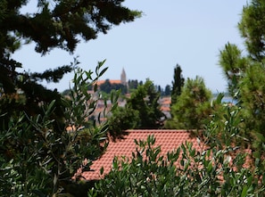 Vista de um edifício com telhado de telhas vermelhas, cercado por vegetação e árvores.