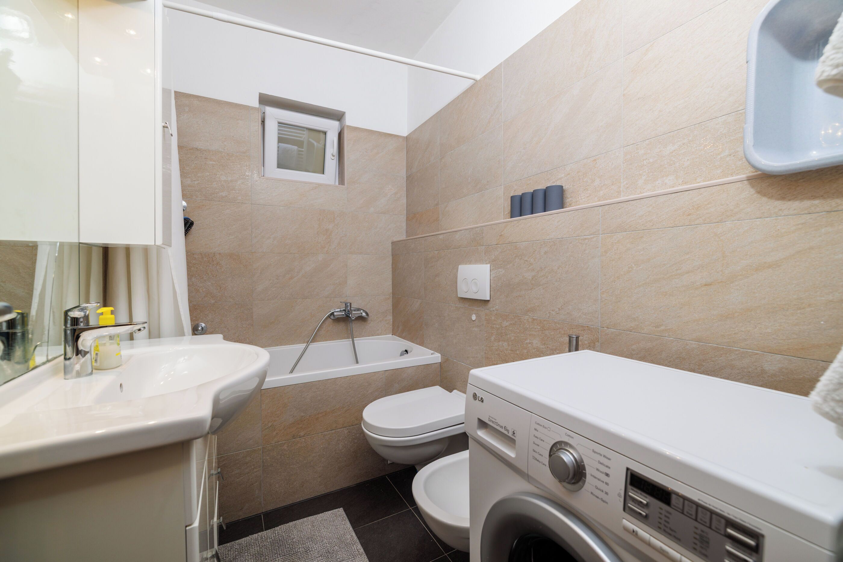 Casa de banho moderna com lavatório, sanita e máquina de lavar roupa.