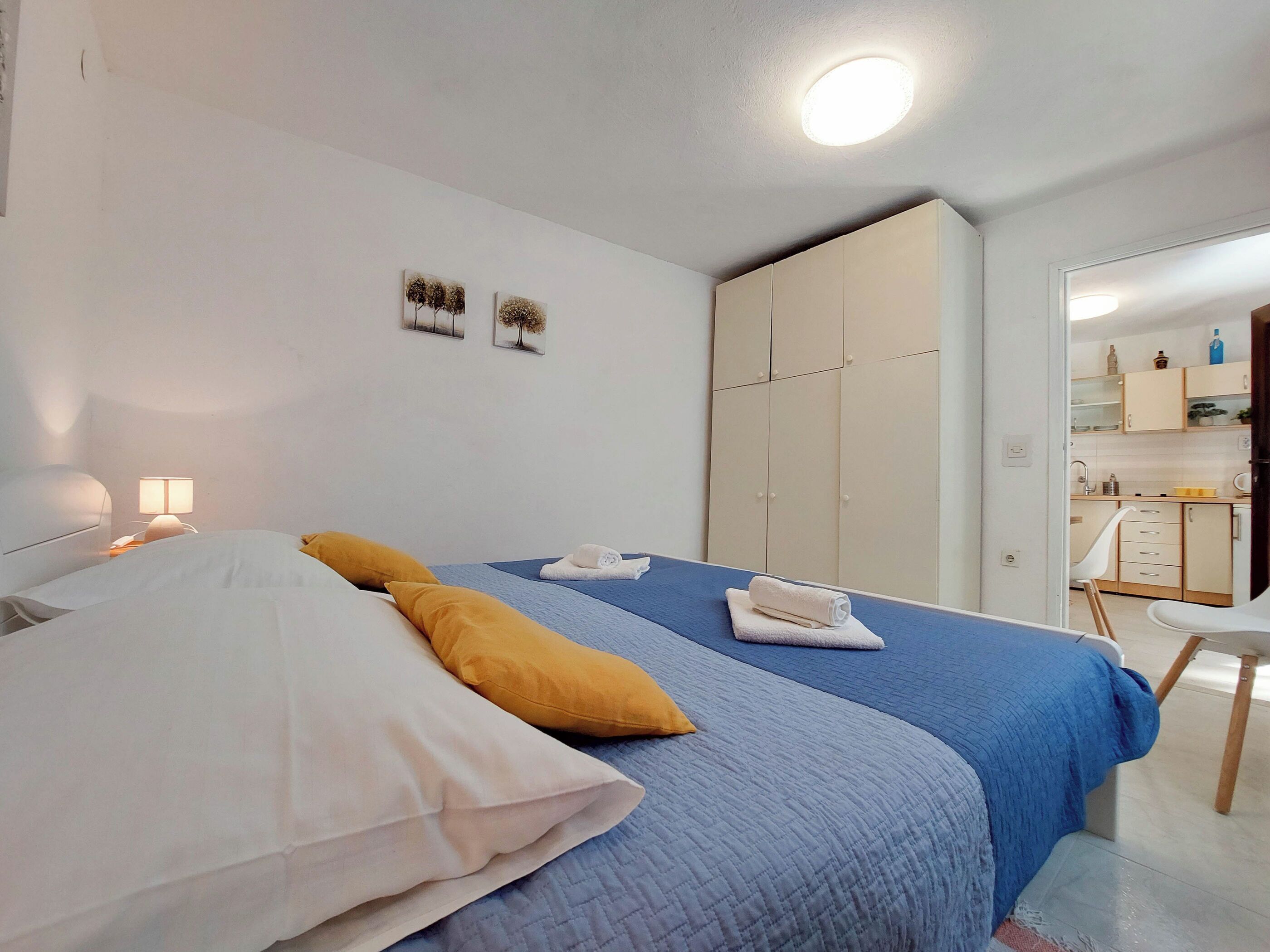 Quarto com duas camas, um guarda-roupa e um banheiro visível por uma porta aberta.