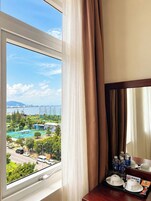 Quarto de hotel com uma janela grande que dá para uma piscina e uma vista da cidade.