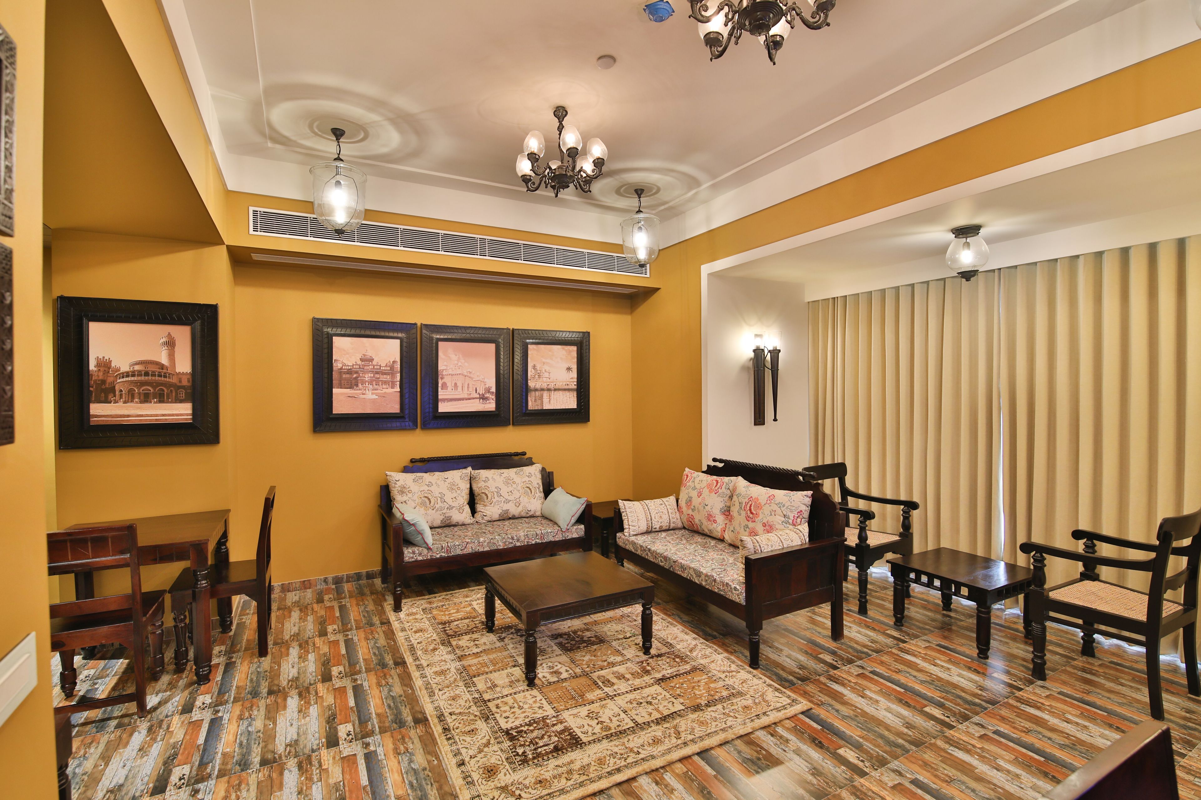 Uma sala de estar com um tapete estampado, móveis de madeira e quadros nas paredes.