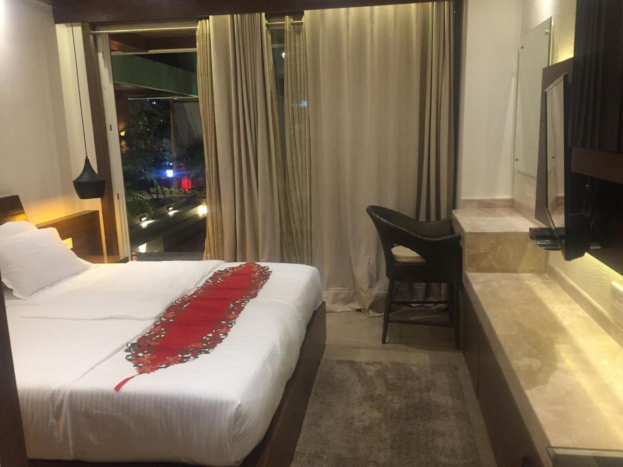 Quarto de hotel com cama, secretária, cadeira e televisão.