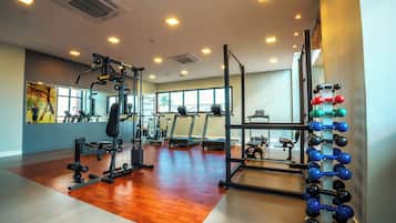 Uma academia com equipamentos de ginástica, esteiras e uma parede espelhada.