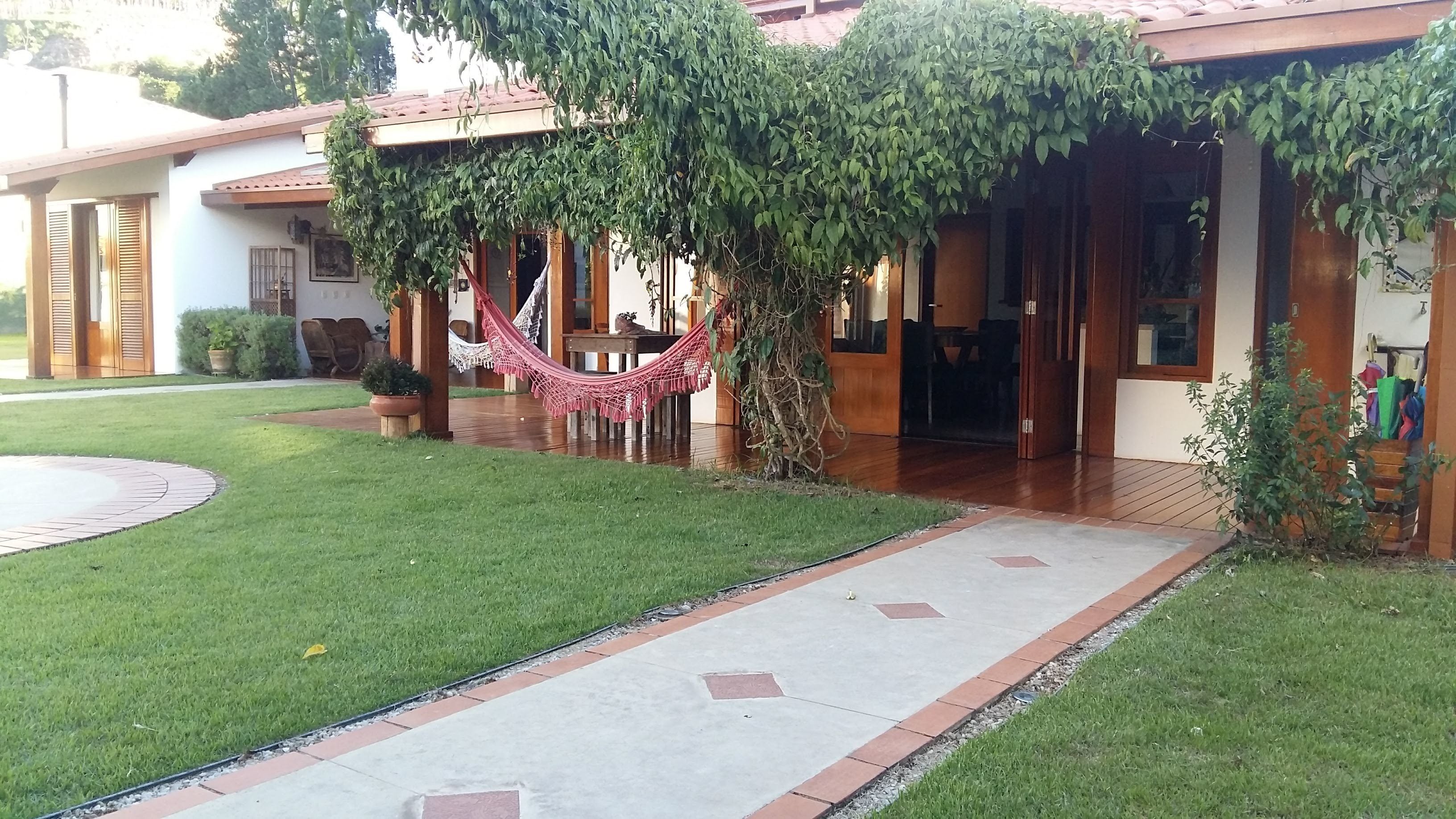 Uma casa com um alpendre, uma rede e um gramado bem cuidado.
