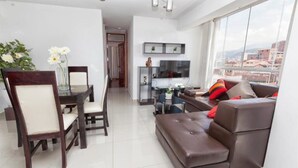 Uma sala de estar moderna com um sofá de couro marrom, uma mesa de jantar com cadeiras e uma janela grande com vista para a cidade.