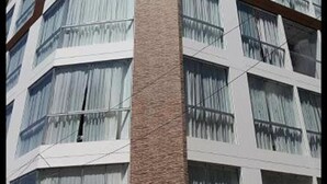 Um edifício alto e moderno, com vários andares, apresentando uma coluna vertical central e inúmeras janelas.