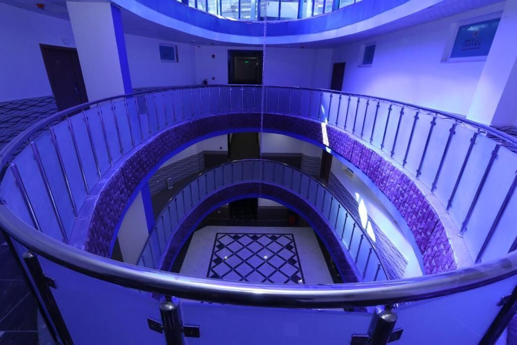 Interior com vários níveis, uma escadaria espiral central e guarda-corpo de vidro.