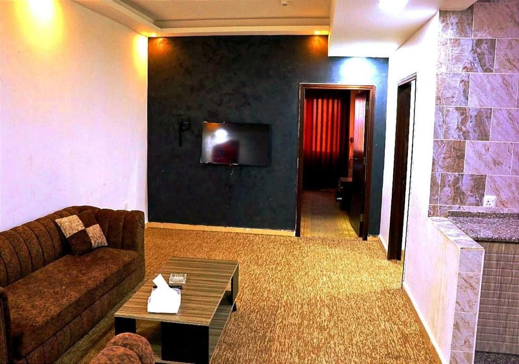 Sala de estar com sofá, mesa de centro, TV de tela plana na parede e lareira de pedra.