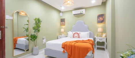 Quarto moderno com cama, mesas de cabeceira, espelho, planta em vaso e ar condicionado.