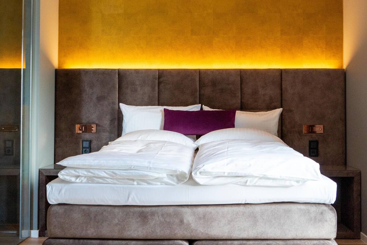 Quarto moderno com uma cama grande, cabeceira com iluminação integrada e design minimalista.