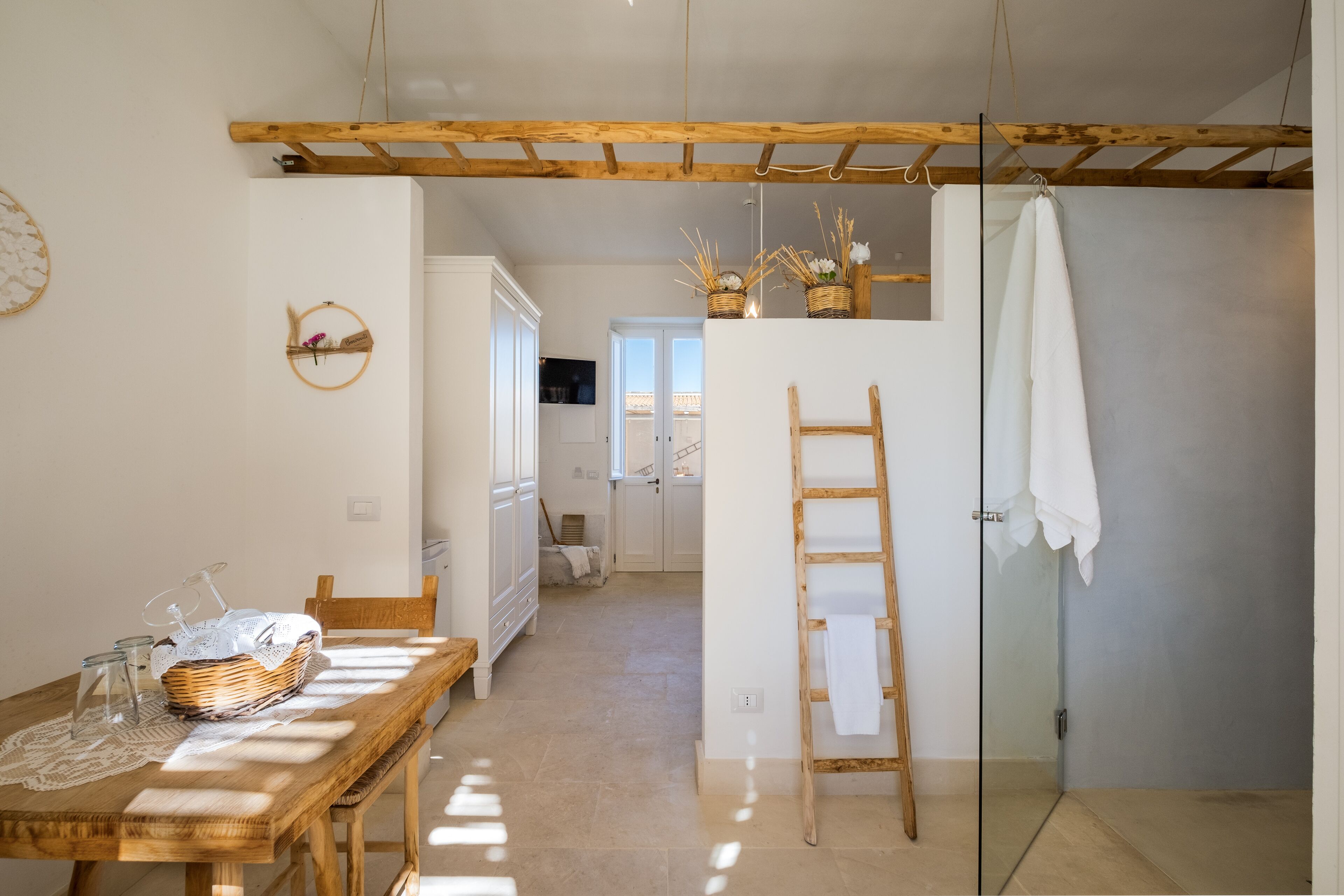 Quarto com mesa de madeira, cesta de vime e escada que dá para o chuveiro.