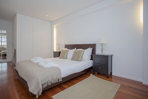 Quarto moderno com uma cama grande, mesas de cabeceira e esquema de cores neutras.