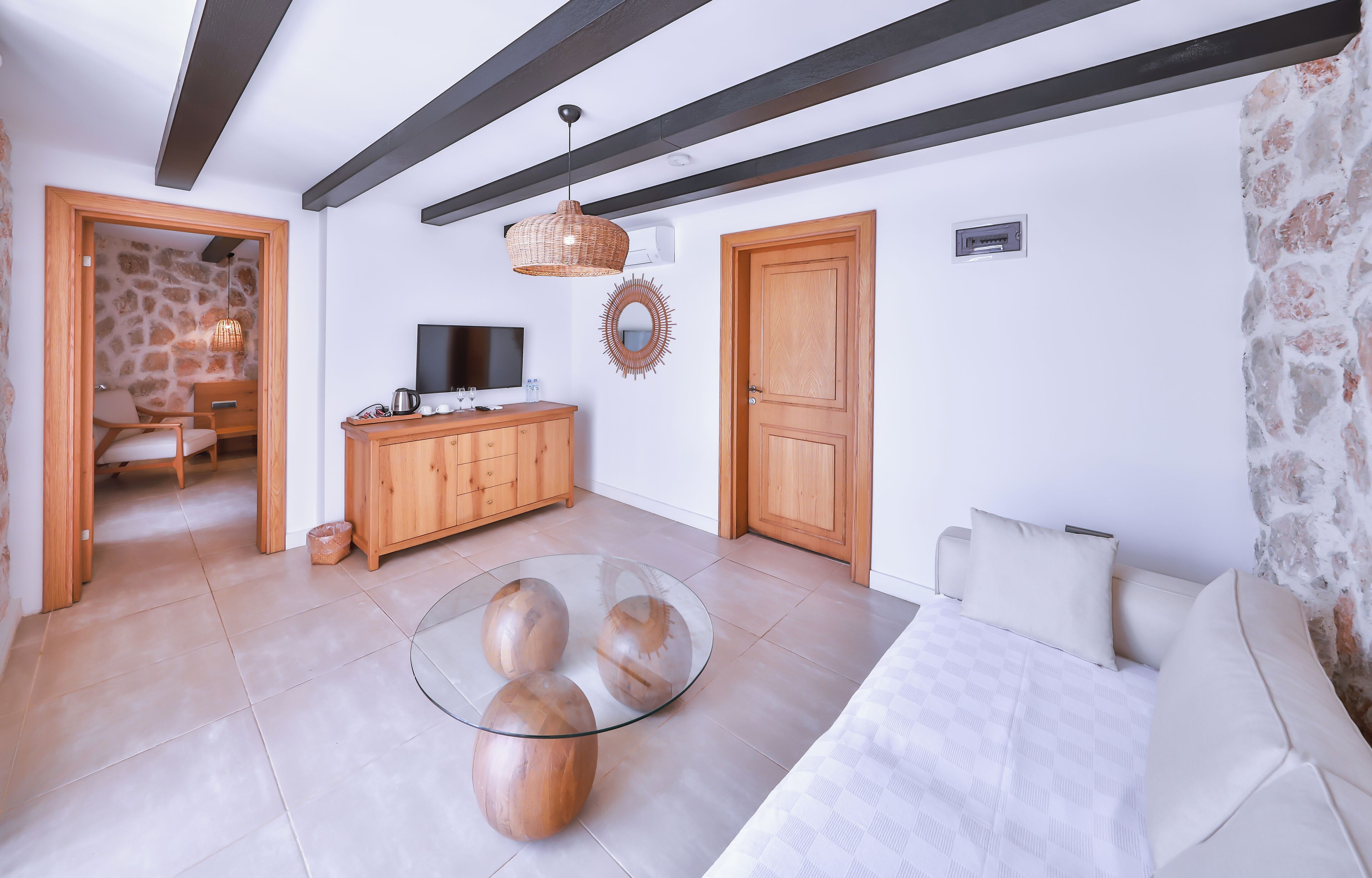 Uma sala de estar moderna com uma mesa de centro de vidro, um sofá, um armário de madeira e uma televisão.