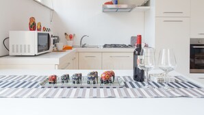 Cozinha moderna com micro-ondas, máquina de café e uma garrafa de vinho. Há pequenas esculturas de elefantes decorativas no balcão.