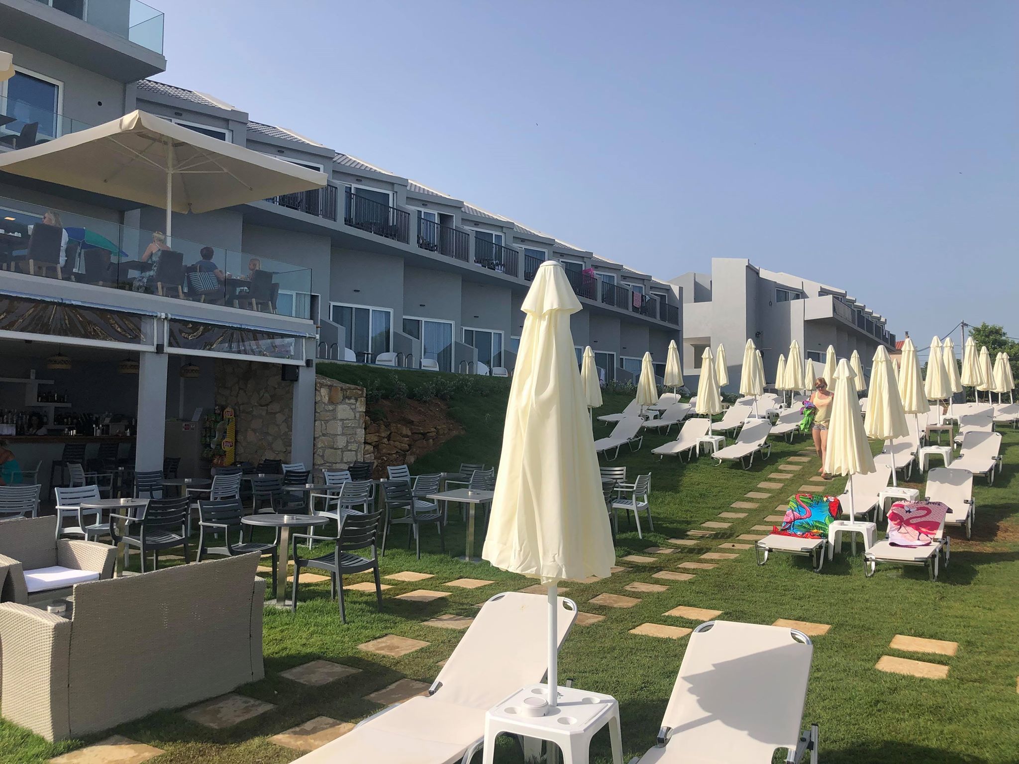 Um resort com áreas de estar ao ar livre, incluindo espreguiçadeiras e guarda-sóis, e um bar com cadeiras e mesas.