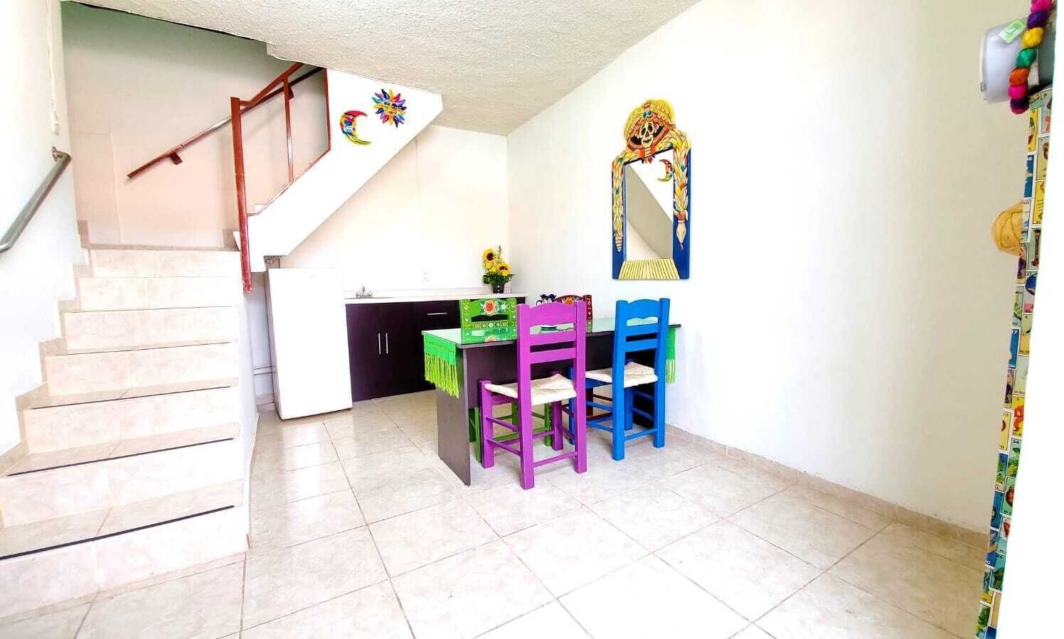 Escada que leva a uma cozinha com mesa e cadeiras.