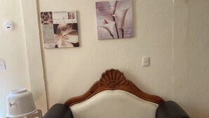 Quarto com um sofá de estilo vintage, uma mesa pequena e duas imagens penduradas na parede.