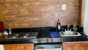Uma cozinha com painel de parede em padrão madeira, pia de aço inoxidável, fogão a gás e armários de madeira.
