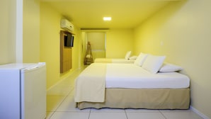 Um quarto pequeno e iluminado, com uma cama, um guarda-roupa e uma televisão.