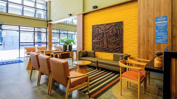 Um lobby moderno com áreas de estar, uma grande janela e um painel decorativo.