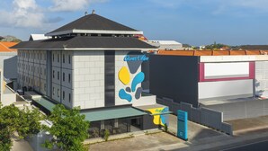 Um edifício moderno com um destaque para a placa 'Quest Vibe', apresentando arte abstrata e uma entrada visível.