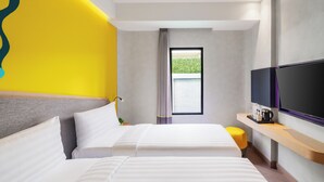 Quarto de hotel moderno com uma cama grande, uma televisão e uma pequena mesa com uma cafeteira.