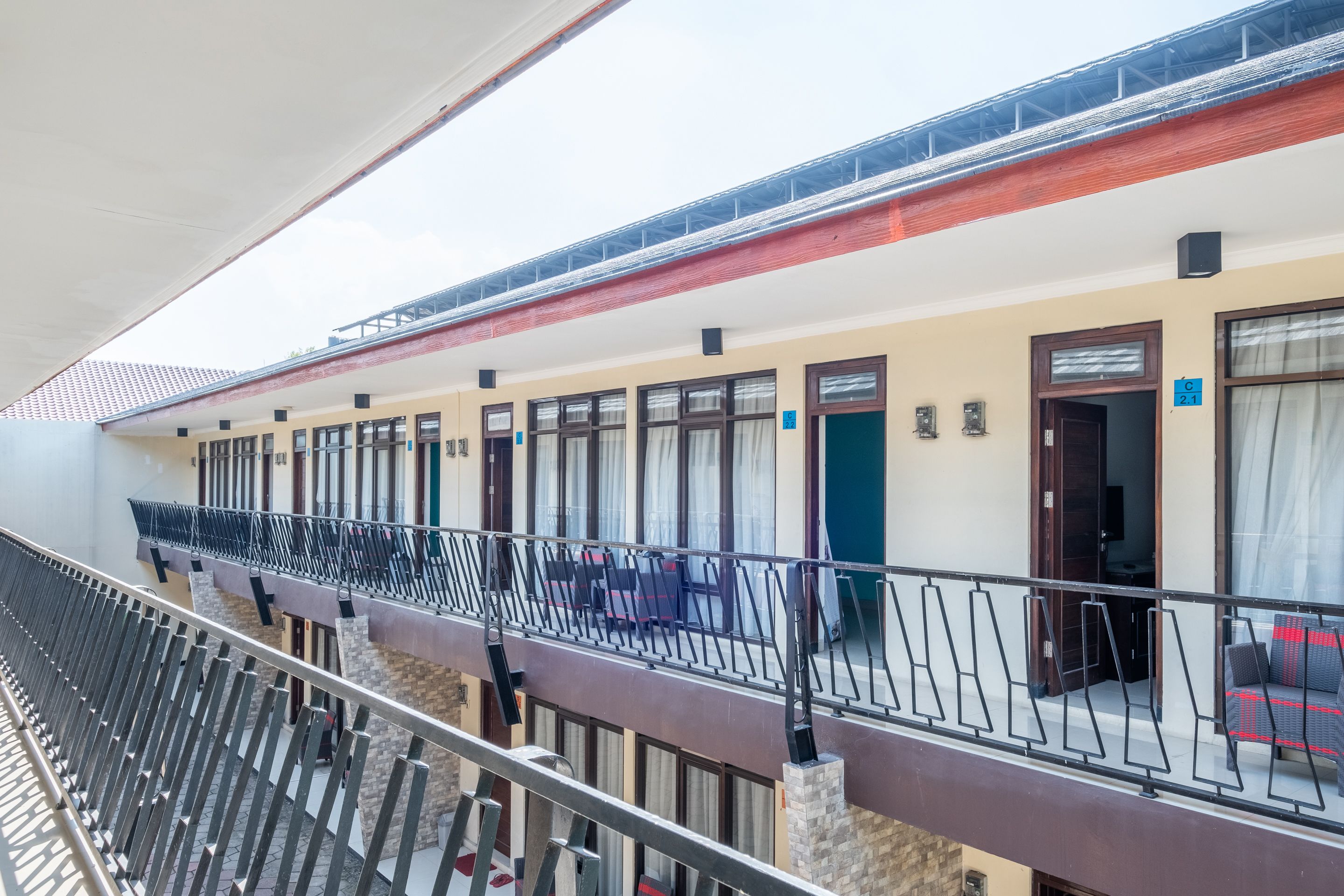 Um hotel com várias varandas, cada uma com guarda-corpo de metal e vista para a rua.
